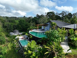 Uma villa privada com piscina, área de estar coberta ao ar livre e vegetação exuberante ao redor da propriedade.