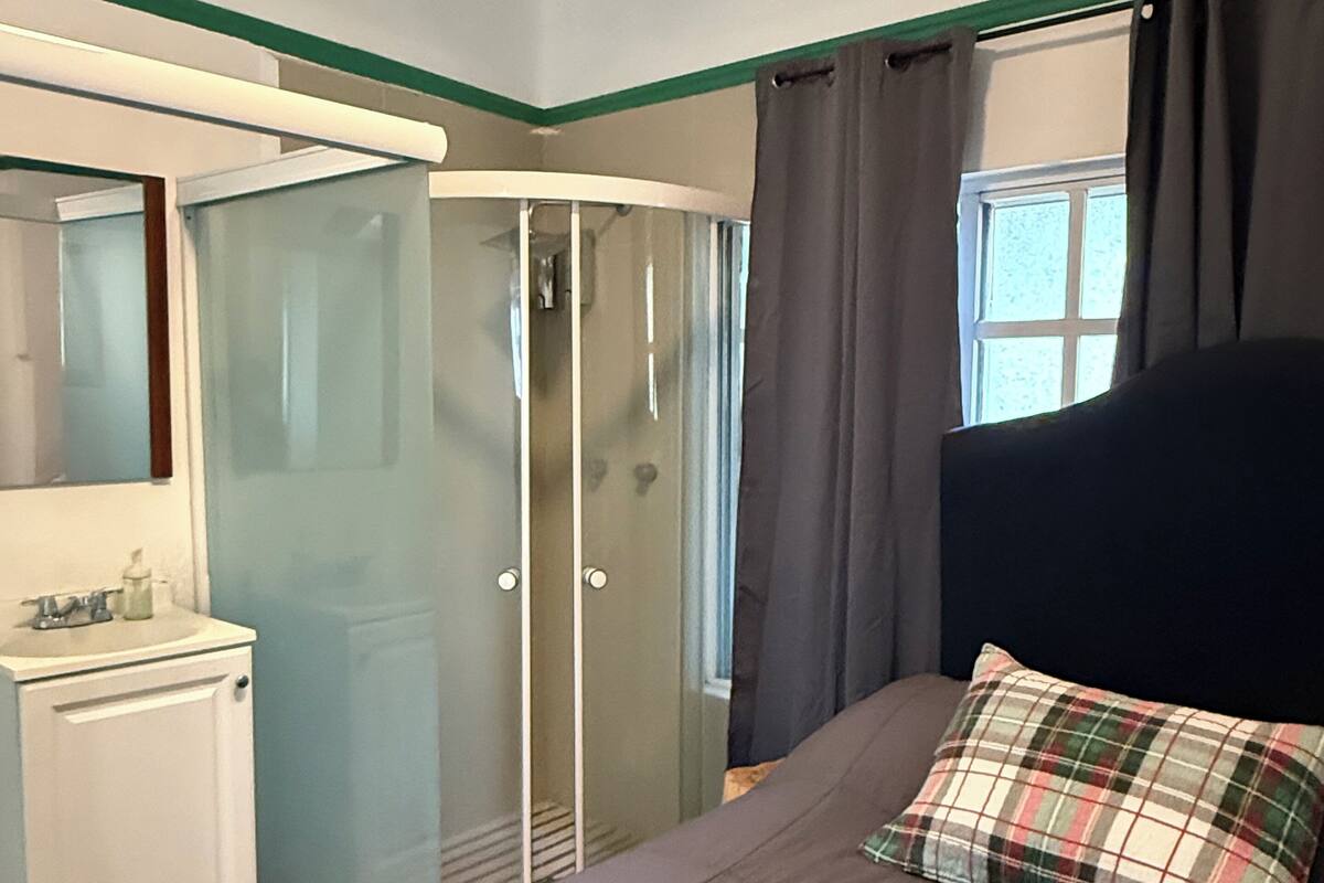 Quarto com cama, guarda-roupa, espelho e janela com cortinas.