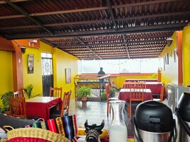 Um restaurante com teto alto, paredes amarelas e vista para o mar.