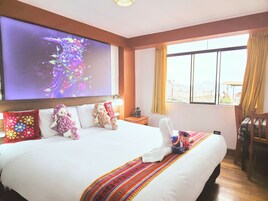 Quarto de hotel com uma cama grande, televisão de tela plana, vista para a cidade e piso de madeira.