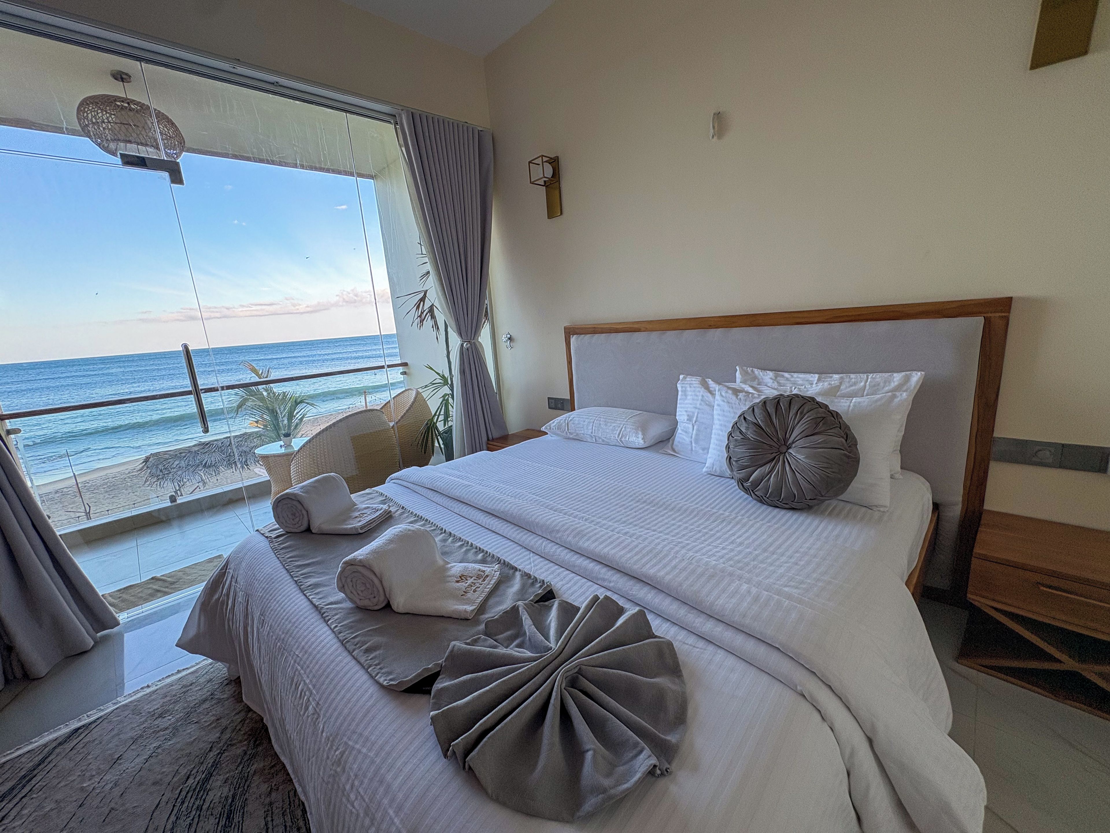 Quarto de hotel com cama, vista para a praia e varanda.