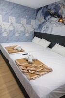 Quarto de hotel com uma cama grande, parede com padrão marmorizado e luminária pendente.