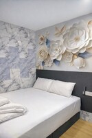 Quarto com uma cama, parede com padrão marmorizado e uma grande decoração floral.