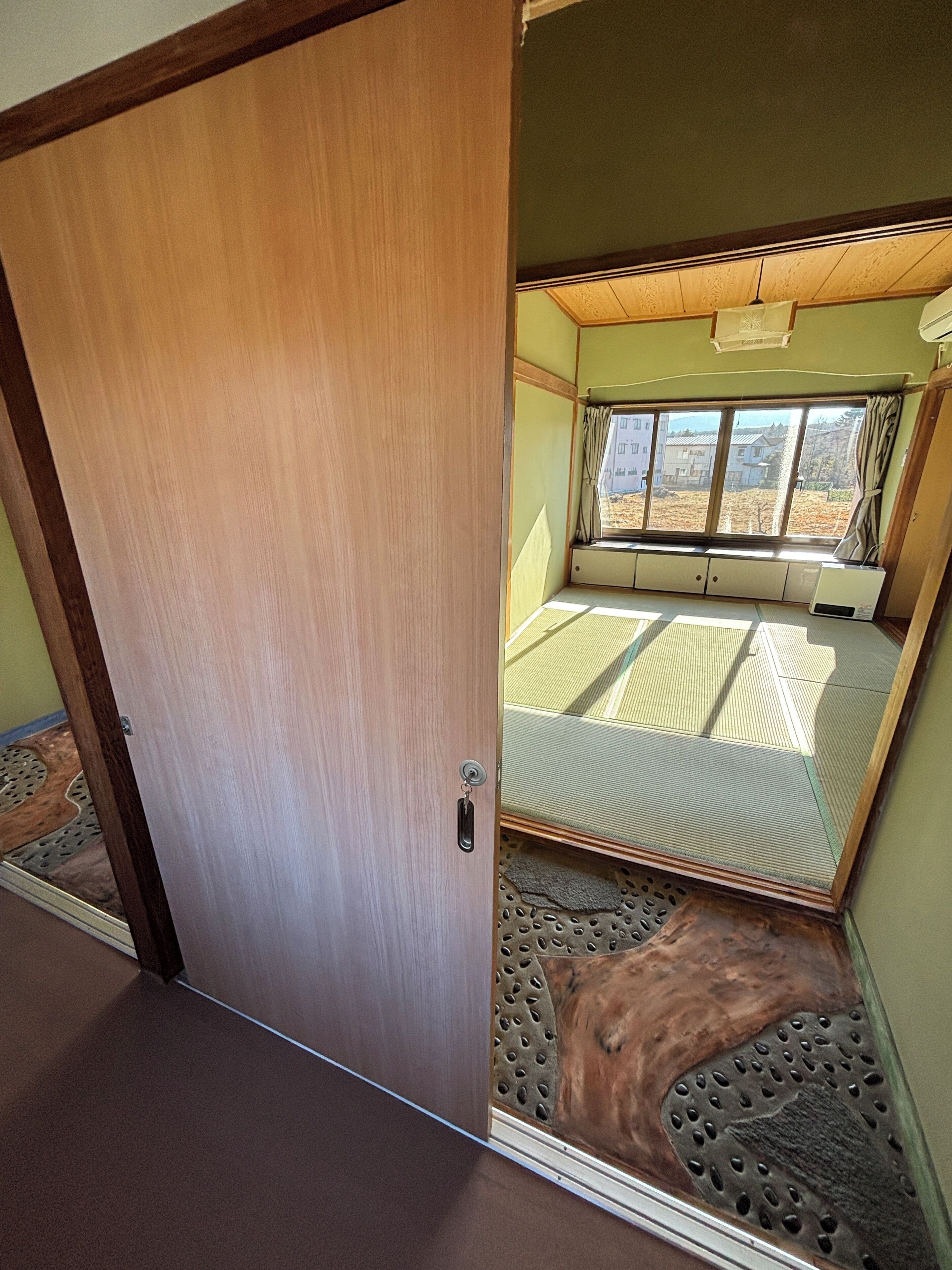 Um quarto com uma cama, uma janela e uma porta.