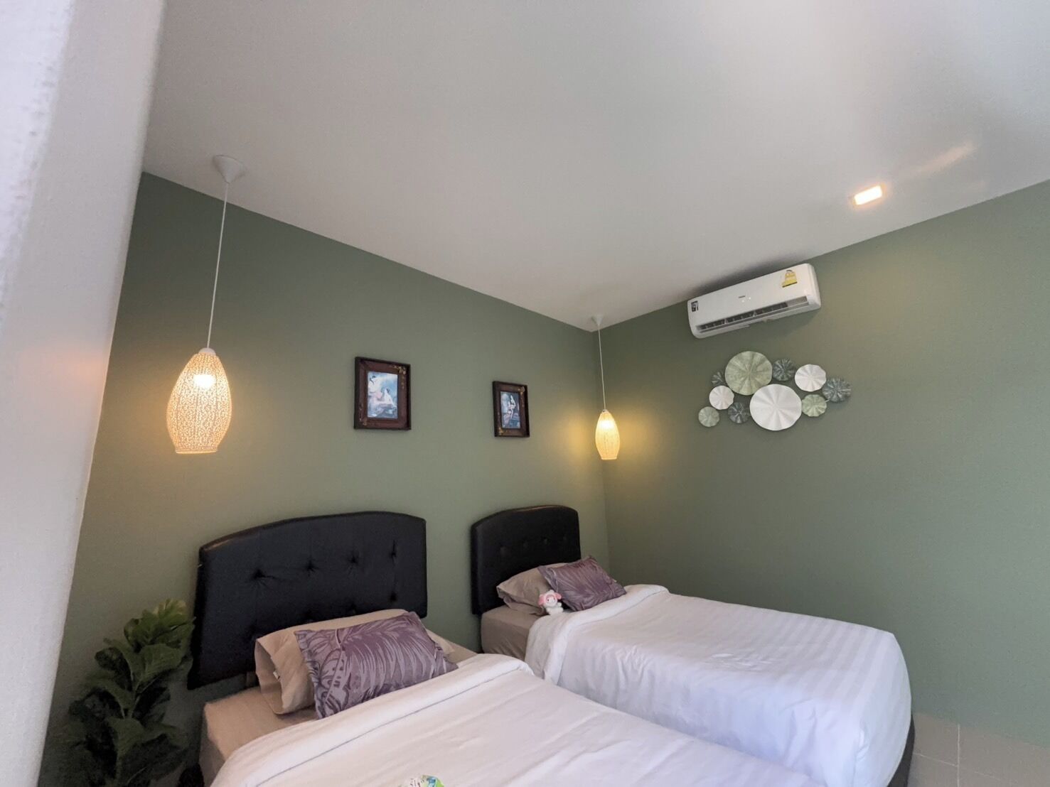Quarto com duas camas, ar-condicionado na parede e luminárias pendentes.