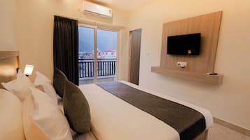 Quarto de hotel com cama, televisão na parede e varanda com vista.