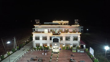Um hotel de vários andares com um pátio central, área de estar ao ar livre e uma placa indicando ser o Vaishnavi Resort.