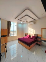 Quarto com cama, guarda-roupa, cadeira, janela e ar condicionado.