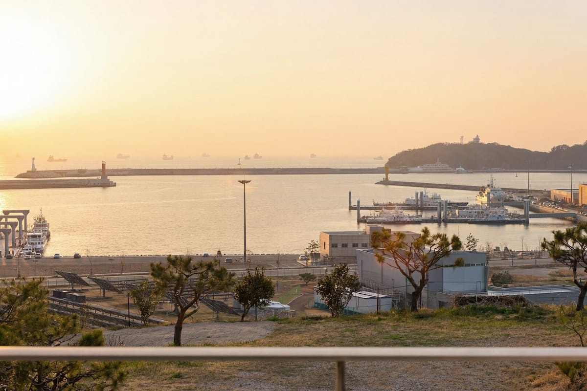 Vista costeira com um porto, navios e edifícios industriais.