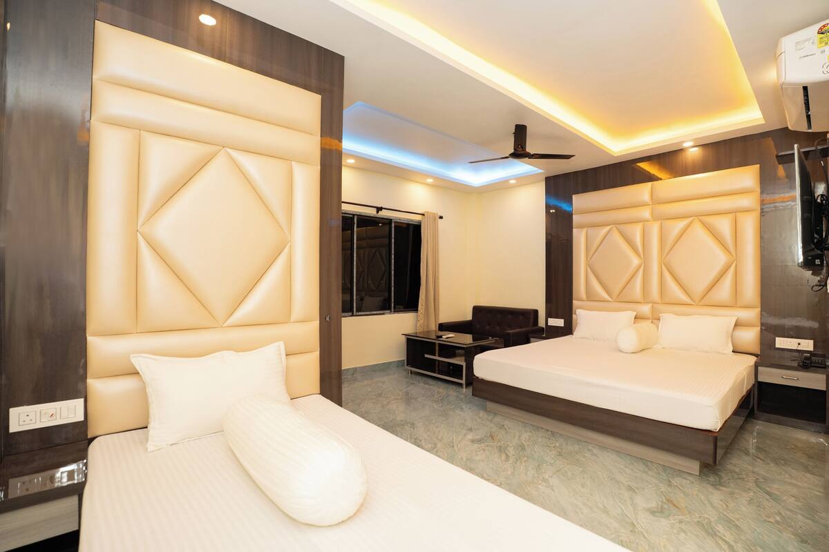 Quarto de hotel moderno com cama grande, área de estar, televisão e guarda-roupa.