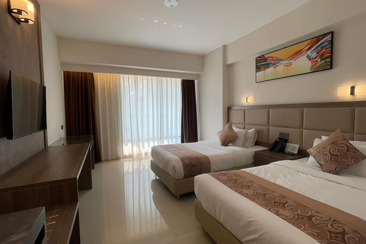 Quarto de hotel com duas camas, televisão, escrivaninha e um quadro na parede.