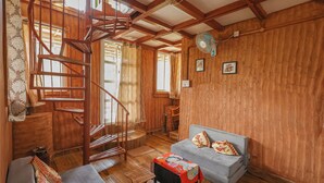 Um interior em madeira com uma escada, um sofá e um ventilador.