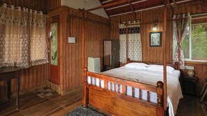 Uma cama de madeira com dossel, colchão branco, guarda-roupa de madeira e um radiador.
