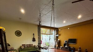 Uma sala de estar com balanço, televisão e lareira de pedra.