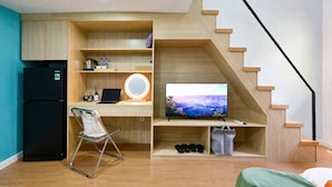 Quarto moderno com escrivaninha, computador, TV e escada.
