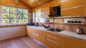 Uma cozinha com armários de madeira, bancada, fogão e janela com vista para árvores.