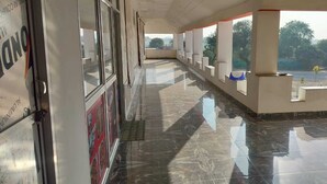Corredor com piso espelhado, balcão de recepção e vista para o exterior.