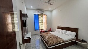 Quarto com cama, mesa de cabeceira e ventoinha no teto.