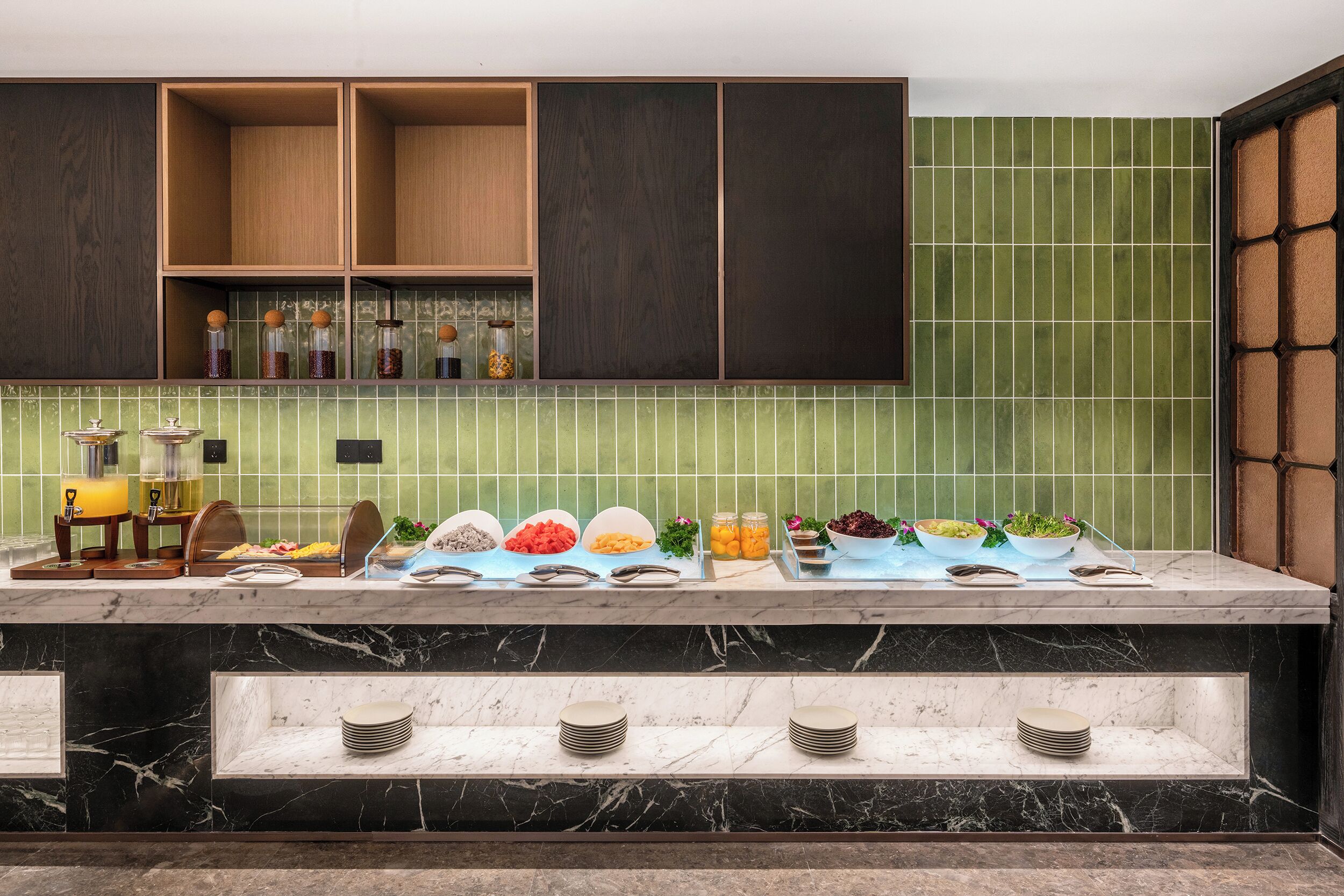 Cozinha com bancadas de mármore, armários de madeira e painel de azulejos verdes.