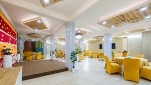 Um amplo hall de hotel com várias áreas de estar, um balcão de recepção e um palco.