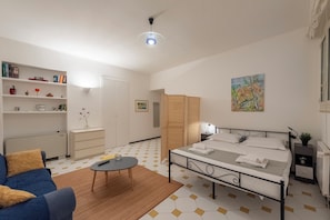 Um quarto com cama, mesa de cabeceira, abajur e guarda-roupa.