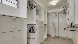 Um closet espaçoso com organizadores para pendurar, uma sacola de roupa e um chuveiro com cortina estampada.