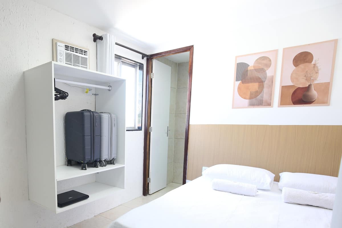 Quarto de hotel com cama, guarda-roupa, espelho e obras de arte na parede.