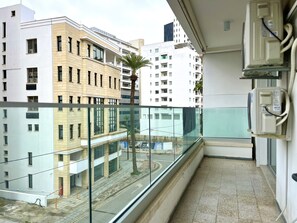 Uma varanda com vista para o horizonte urbano, incluindo edifícios altos e uma palmeira.