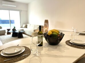 Uma mesa de jantar com uma cesta de frutas, uma garrafa de vinho e taças de vinho.