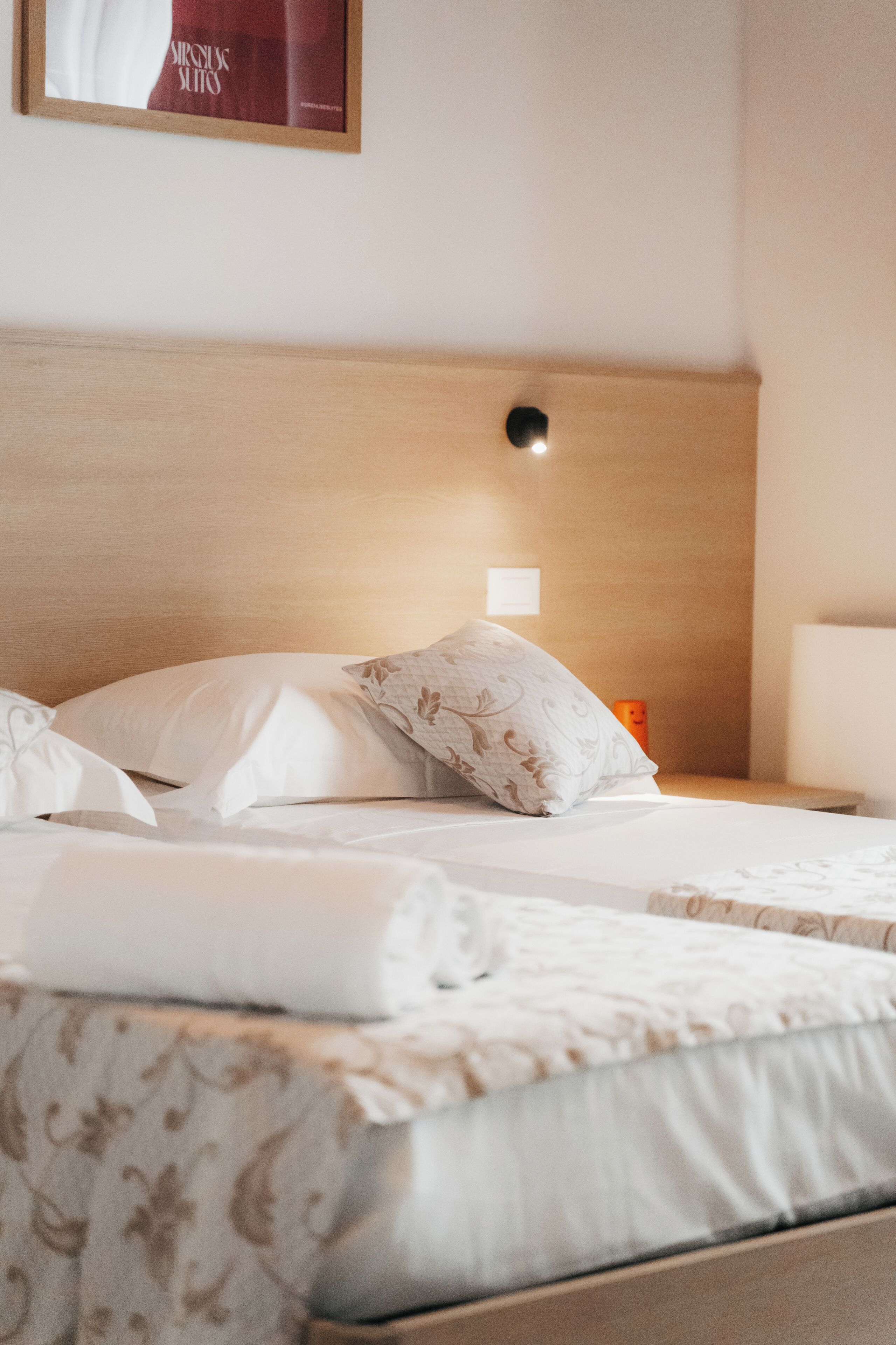 Cama bem arrumada com cabeceira, travesseiros e mesa de cabeceira com abajur.