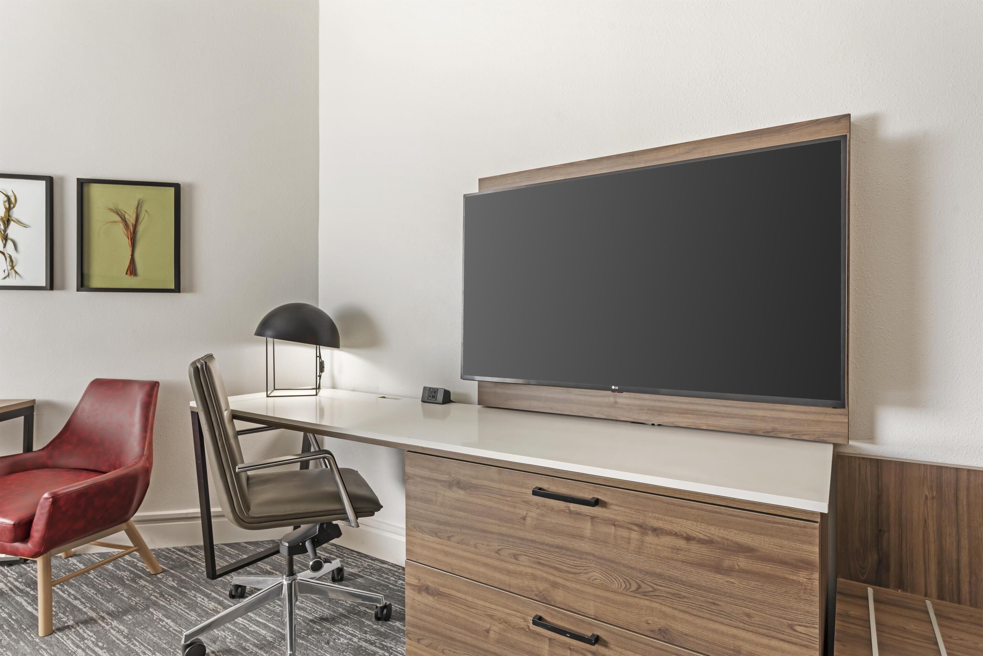 Um espaço de escritório moderno com uma mesa, uma cadeira e um quadro negro grande.
