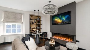 Uma sala de estar moderna com lareira, área de jantar e uma grande janela.