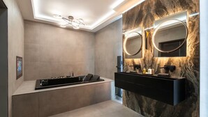 Casa de banho moderna com toucador preto, dois espelhos e parede de mármore.