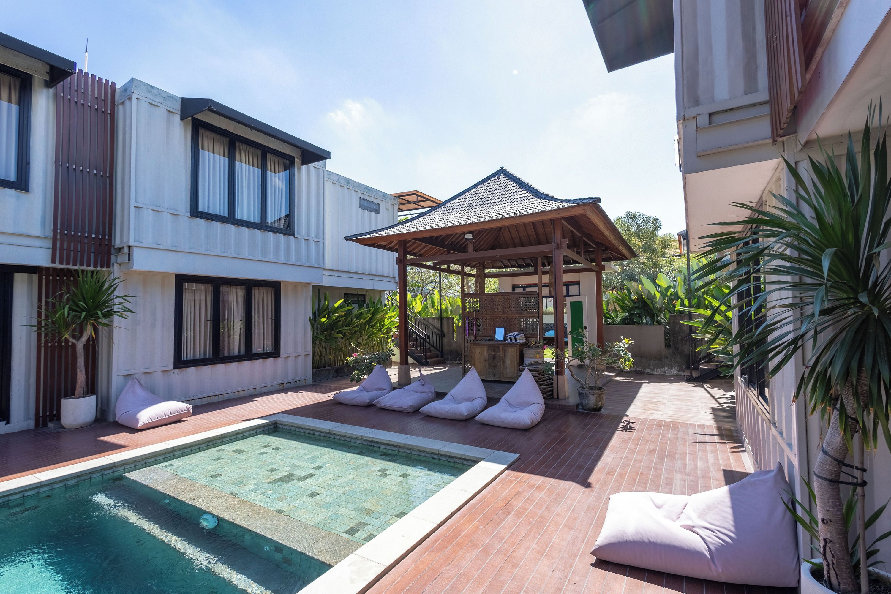 Uma área moderna com piscina ao ar livre, deck de madeira, espreguiçadeiras e um espaço de estar coberto.