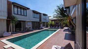 Um moderno imóvel residencial com piscina, área de estar externa e um terraço coberto.