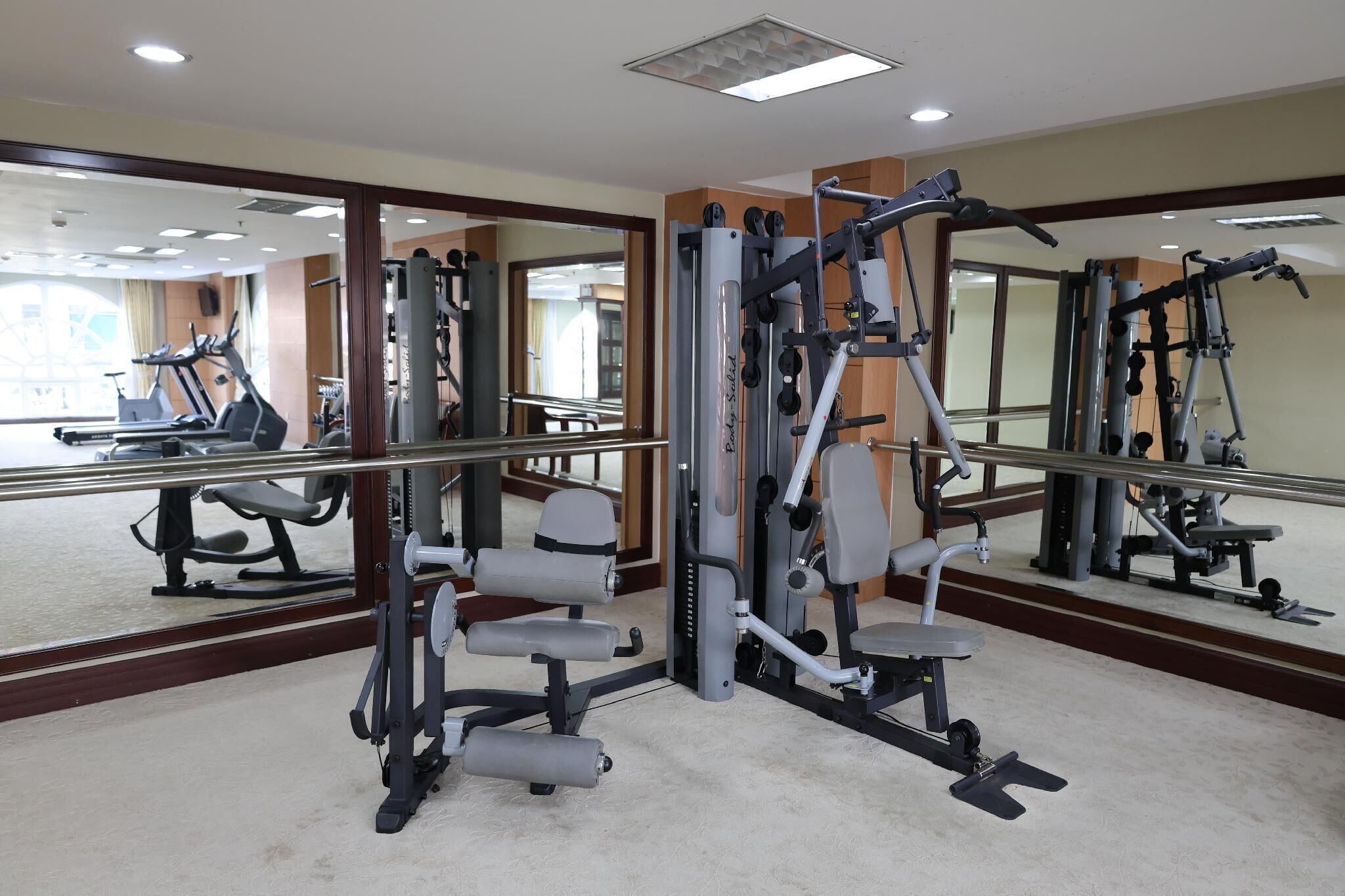 Uma academia com equipamentos de ginástica, espelhos e vista para o exterior.