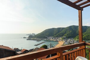 Uma vila costeira com uma varanda de madeira com vista para o mar, edifícios e colinas.