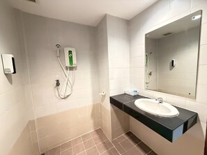 Uma casa de banho moderna com lavatório branco, espelho e chuveiro manual.