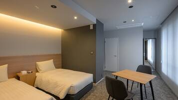 Quarto de hotel com duas camas, uma mesa e uma cadeira.