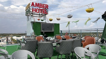 Uma área de estar externa com uma placa indicando 'AMBER HOTEL' e vista para a paisagem.