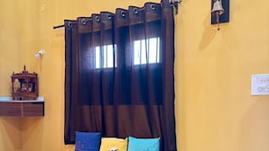 Quarto com cama, uma mesinha, um armário e um sino fixado na parede.
