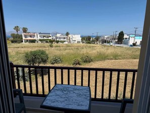 Uma varanda com uma mesa de mármore, com vista para um campo gramado e edifícios.