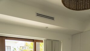 Uma cozinha moderna com uma ilha grande, banquetas de bar, uma planta em vaso e uma porta de vidro deslizante que dá para uma área de piscina.