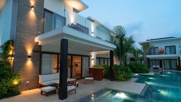 Uma casa moderna de dois andares com piscina, área de estar externa e varanda bem iluminada.