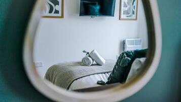 Quarto com cama, TV fixada na parede e ar condicionado também na parede.