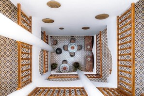 Um quarto com um chão estampado, uma mesa central com cadeiras e uma parede decorativa.