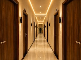 Corredor de hotel com portas de madeira, placas de número de quarto e piso de mármore polido.