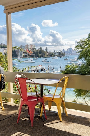 Varanda com mesa e cadeiras com vista para um porto com barcos e edifícios.