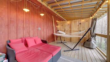 Uma cabana de madeira com uma cama, uma rede e vista para o exterior.
