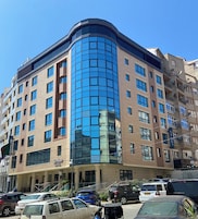 Um hotel com fachada de vidro curvo, várias varandas e entrada no nível da rua.